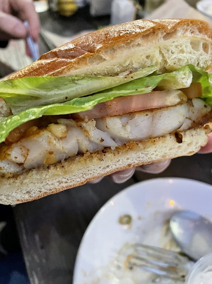 The star of the show in cross-section glory. Flaky white grouper nestled between crisp lettuce and pillowy bread &ndash; architectural perfection on a plate.