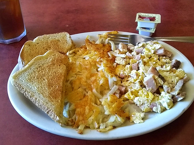Hash browns crisped to golden perfection, eggs scrambled with ham, and toast that clearly understands its supporting role in this breakfast drama.