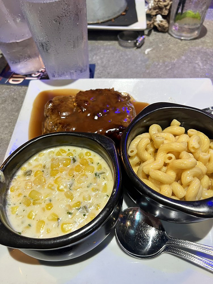 Mom's meatloaf arrives swimming in savory gravy alongside creamy mac and cheese and corn. This isn't just comfort food&mdash;it's a warm hug on a plate after a long day.