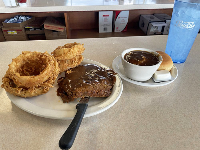 Behold the star attraction: meatloaf that makes grandmothers nervous about their family recipe status, accompanied by onion rings that shatter like delicate glass.