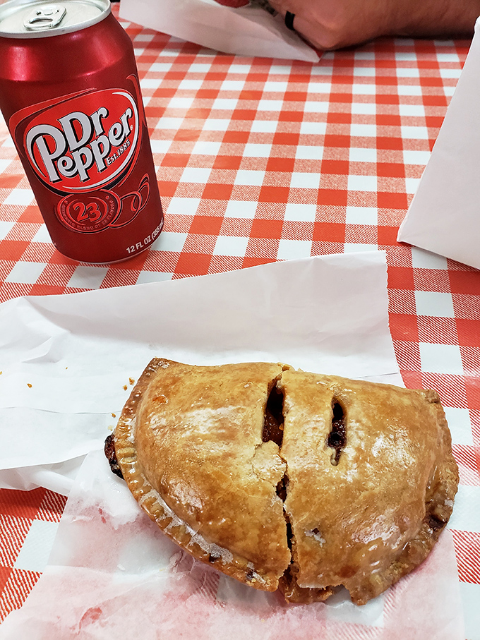 The perfect Oklahoma pairing: a flaky fried pie and an ice-cold Dr Pepper on a checkered tablecloth. Norman Rockwell couldn't paint a more American scene.
