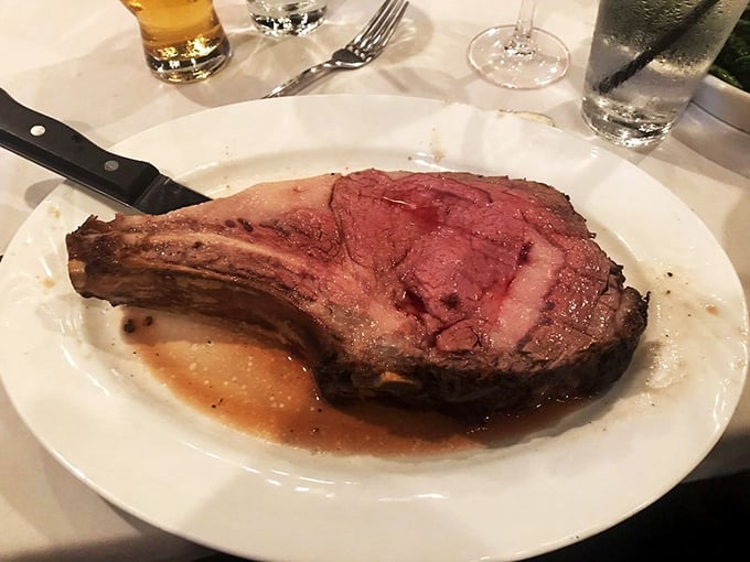 The prime rib arrives like a carnivore's dream – perfectly pink, swimming in au jus, with a bone that says "I mean business."