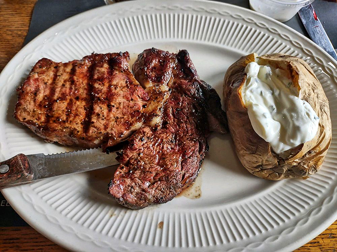 Behold the ribeye in its natural habitat&mdash;perfectly charred exterior, juicy interior, and a baked potato sidekick that's dressed for success.