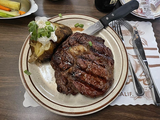 Behold the ribeye in its natural habitat&mdash;perfectly charred exterior, pink interior, and a baked potato sidekick worthy of its own fan club.