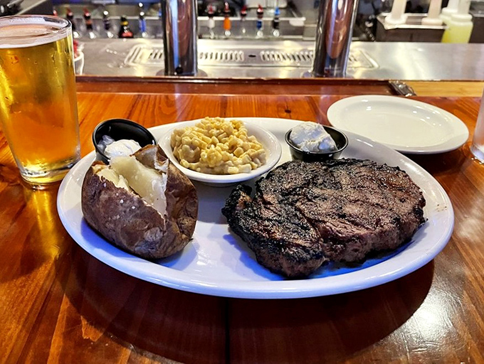 A perfectly charred ribeye alongside a loaded baked potato and mac & cheese—the holy trinity of comfort food that makes Monday feel like Saturday.