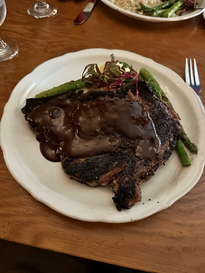This isn't just a steak; it's a masterclass in carnivorous delight. The rich sauce cascading over perfectly charred beef alongside bright asparagus creates edible poetry.