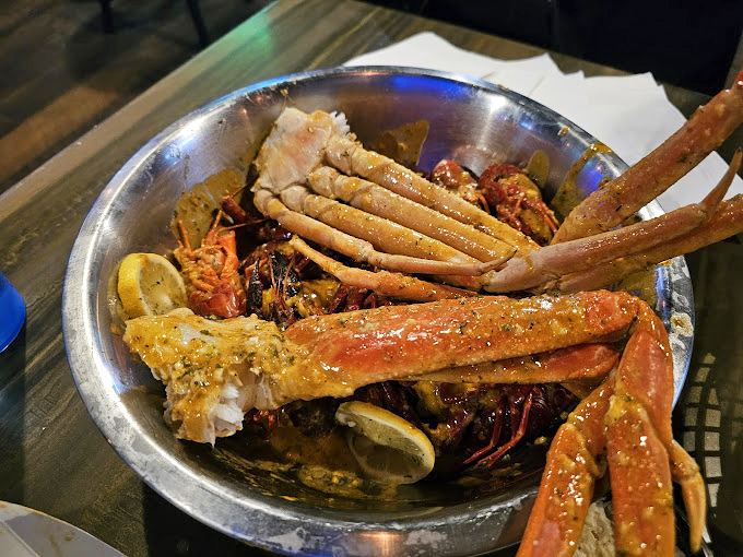 Snow crab legs and crawfish having a pool party in seasoned broth. The lemon wedges aren't just garnish&mdash;they're essential equipment for this seafood safari.