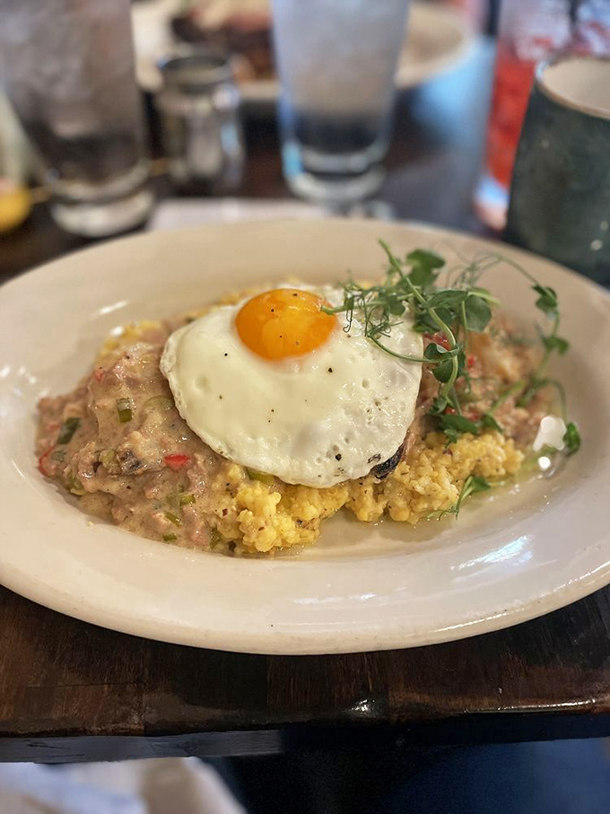 Breakfast nirvana achieved: creamy grits, perfectly cooked shrimp, and a sunny-side egg that's basically wearing a superhero cape.