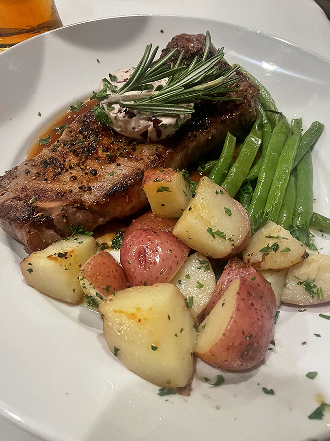 A perfectly cooked steak garnished with fresh rosemary shares the plate with colorful potatoes and vibrant green beans&mdash;a trio that performs in perfect harmony.