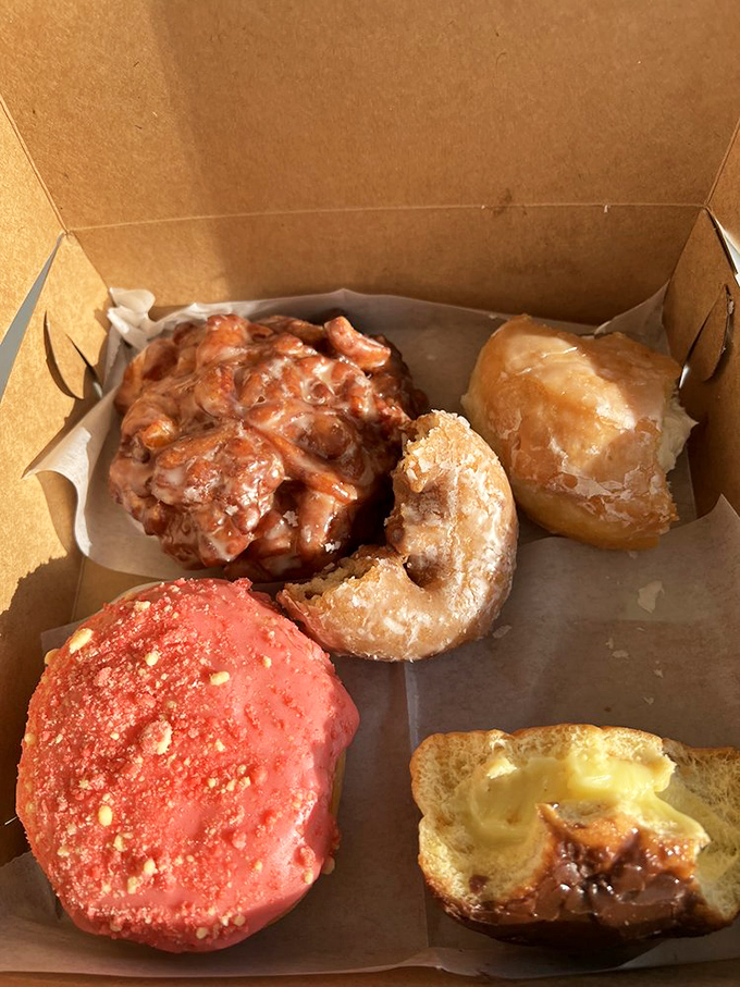 The mark of true donut royalty: that perfect apple fritter nestled among its glazed cousins in a humble cardboard throne.
