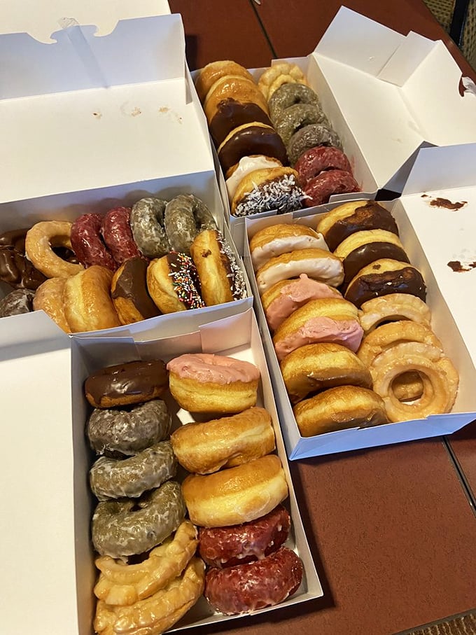 Three boxes of donuts arranged like a triptych of Renaissance art, if Michelangelo had worked in sugar and dough instead of paint.