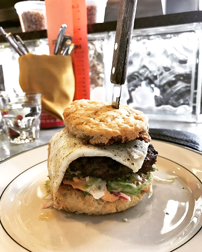 This isn't your drive-thru breakfast sandwich. The architectural marvel balances a perfectly fried egg atop a burger that would make fast food mascots weep with envy.