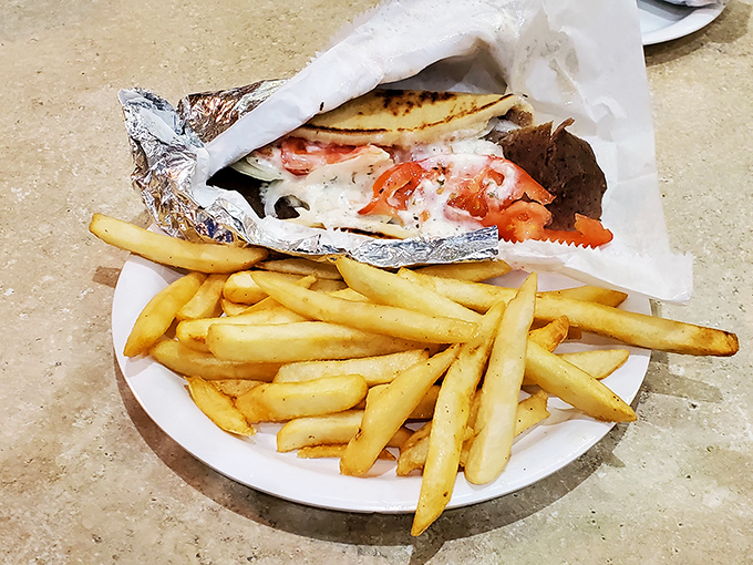 The perfect marriage: a gyro wrapped in foil like a present from the gods, alongside golden fries that demand to be dunked in tzatziki.