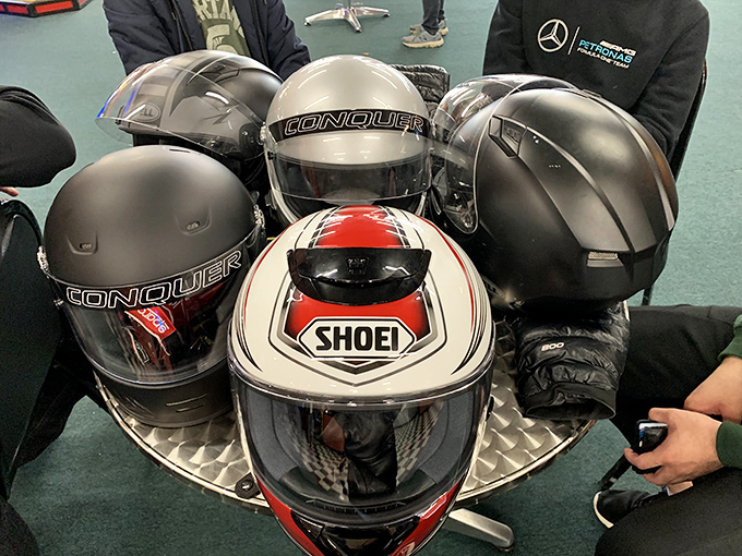 These helmets aren't just safety equipment—they're temporary identity changers that transform ordinary folks into Earnhardts and Andrettis for ten glorious laps.