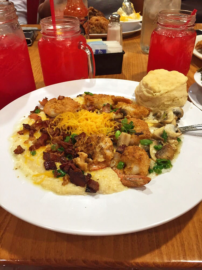 The holy trinity: crimson punch, golden biscuit, and shrimp nestled in grits like they've found their forever home.