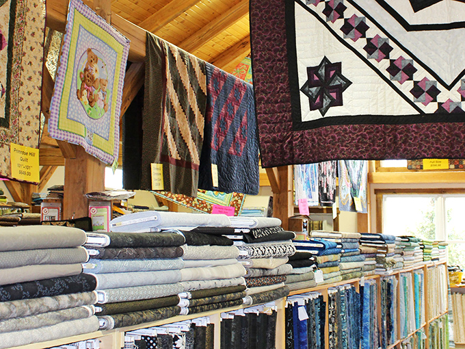 Fabric shelves create a textile library where each bolt tells a different story, with quilted masterpieces hanging overhead as inspiration.