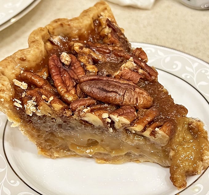 This slice of pecan pie reveals the perfect ratio of gooey filling to crunchy nuts. It's the kind of dessert that makes you consider ordering a second slice before finishing the first.