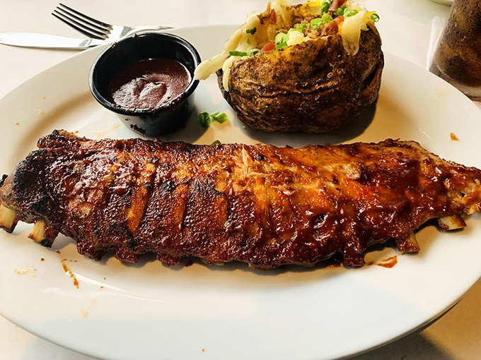 Baby back ribs that balance the primal joy of meat-on-bone with the civilization of a perfect char, alongside a baked potato dressed for its own special occasion.