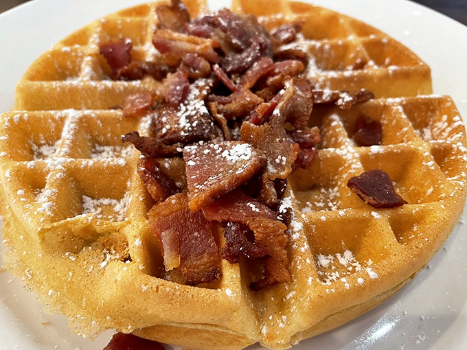 The waffle-bacon relationship reaches its pinnacle here&mdash;crispy, savory bacon bits nestled into golden waffle divots dusted with powdered sugar. Sweet meets savory in breakfast harmony.