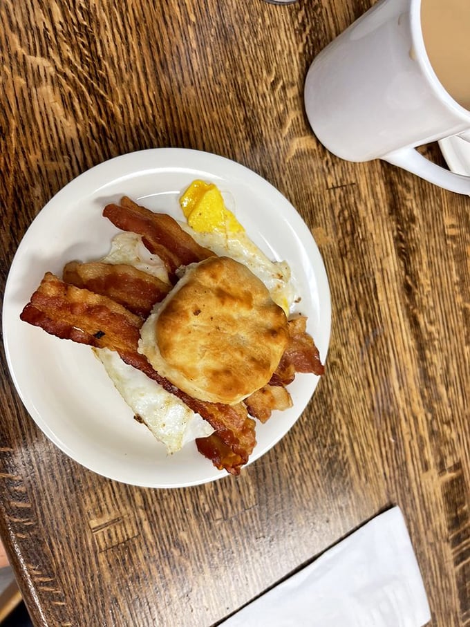 The holy trinity of breakfast: crispy bacon, fluffy biscuit, and a sunny egg. Simple perfection on a plate.
