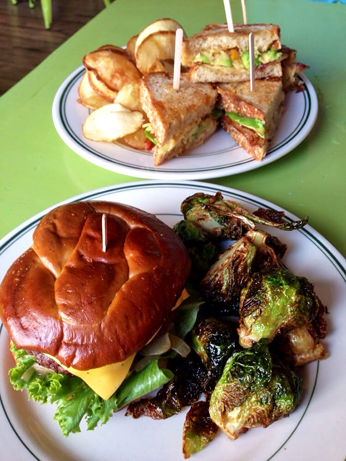 This isn't just lunch, it's edible architecture—perfectly stacked sandwiches with crispy chips and those brussels sprouts that could convert any vegetable skeptic.