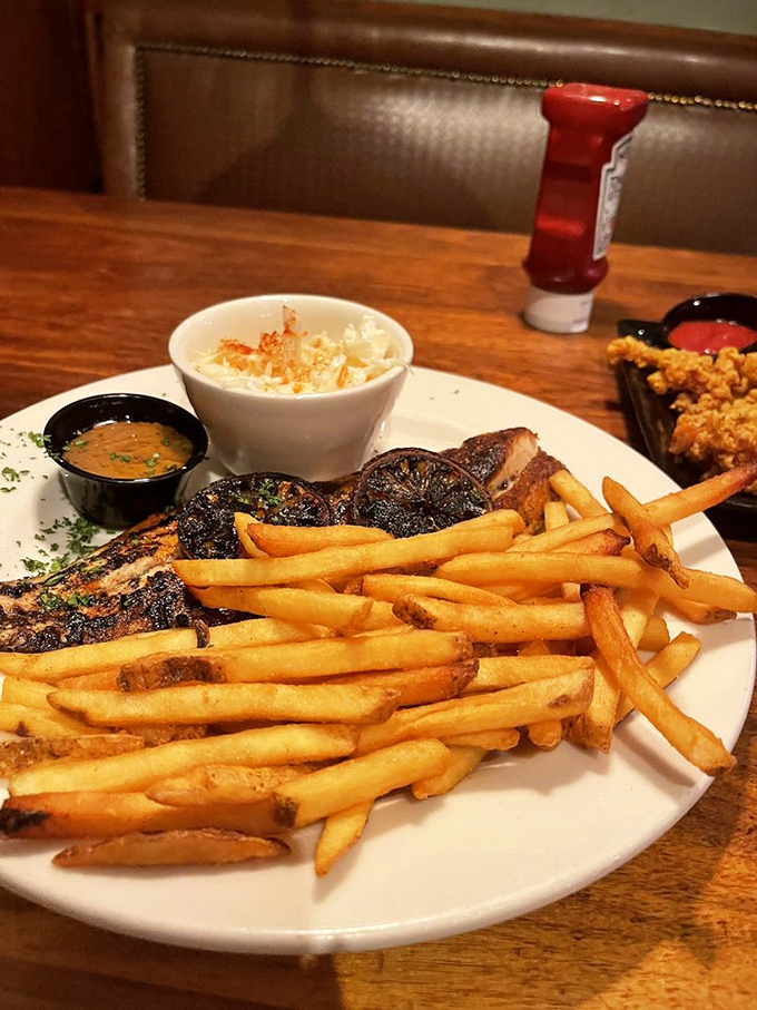 This blackened fish doesn't just sit on the plate &ndash; it commands attention with its spice-crusted exterior, flanked by golden fries standing at attention.