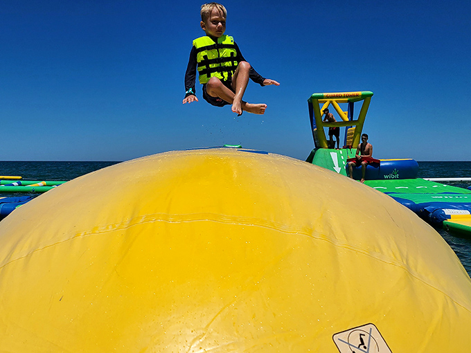 Defying gravity and adulthood simultaneously! A youngster catches air off a yellow bounce platform, demonstrating the perfect combination of courage and buoyancy.
