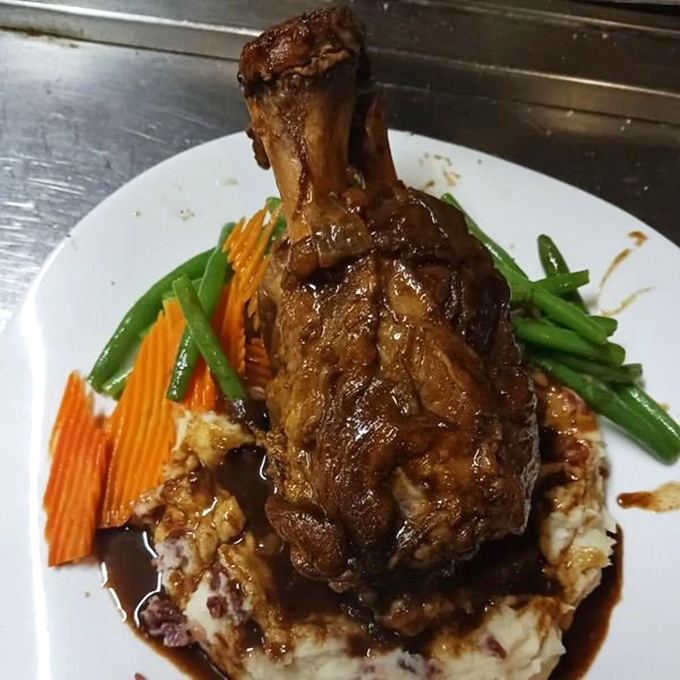 The braised pork shank arrives like a meaty monument to patience, tender enough to make you consider proposing marriage to the chef.