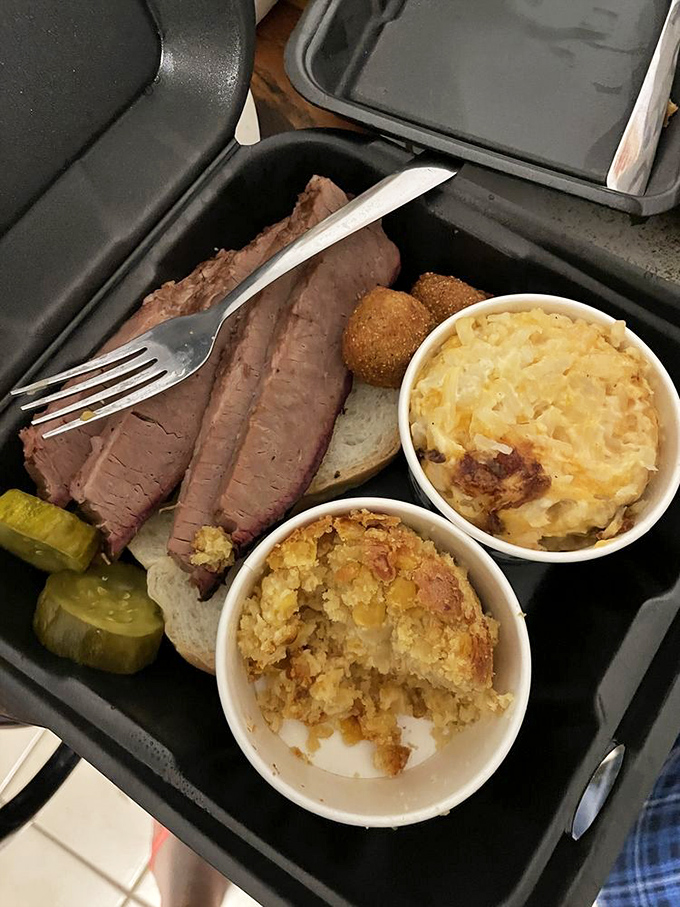 Behold the holy trinity of barbecue bliss: perfectly sliced brisket with that coveted smoke ring, comfort-food sides, and the pickle palate cleanser.