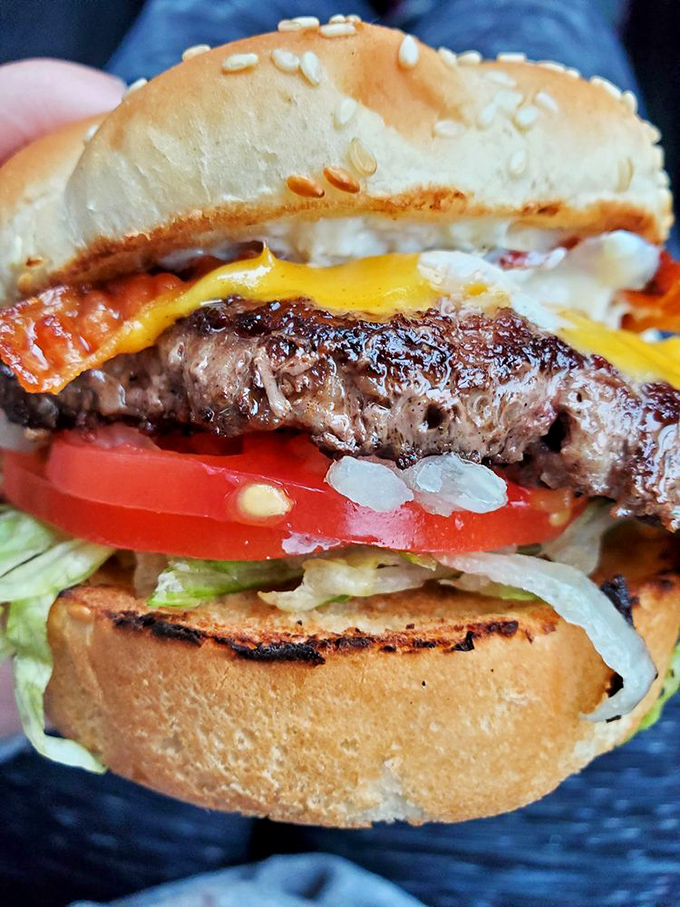 Architecture of deliciousness - layers of beef, bacon, cheese, and fresh veggies on a toasted bun. This isn't just a burger; it's edible poetry.