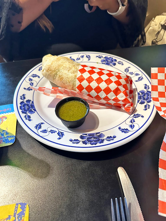 A burrito wrapped in classic red-checkered paper, accompanied by that legendary green sauce &ndash; simplicity that delivers complex pleasure.
