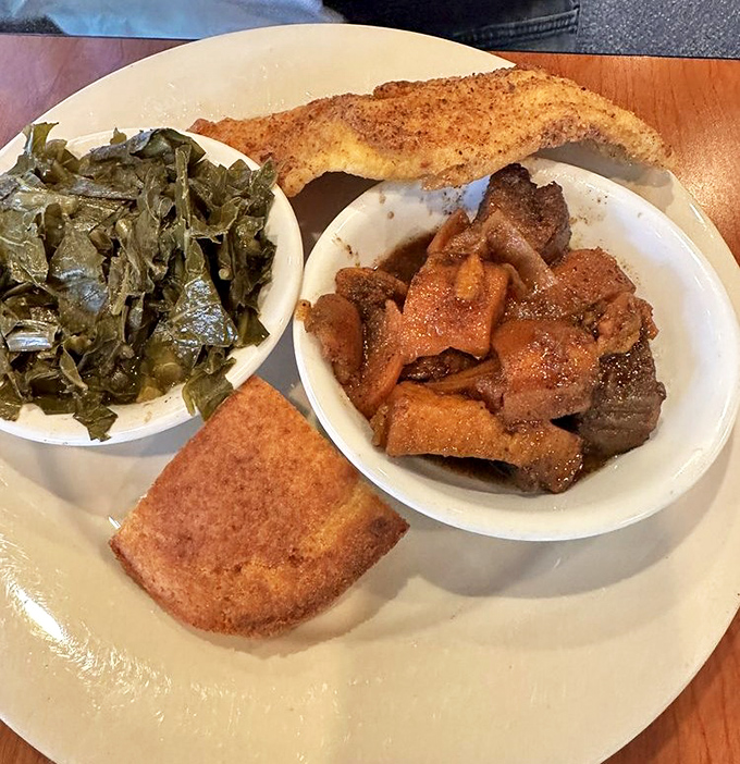 Cornbread, collards, and what appears to be candied yams&mdash;the holy trinity of sides flanking perfectly seasoned catfish.