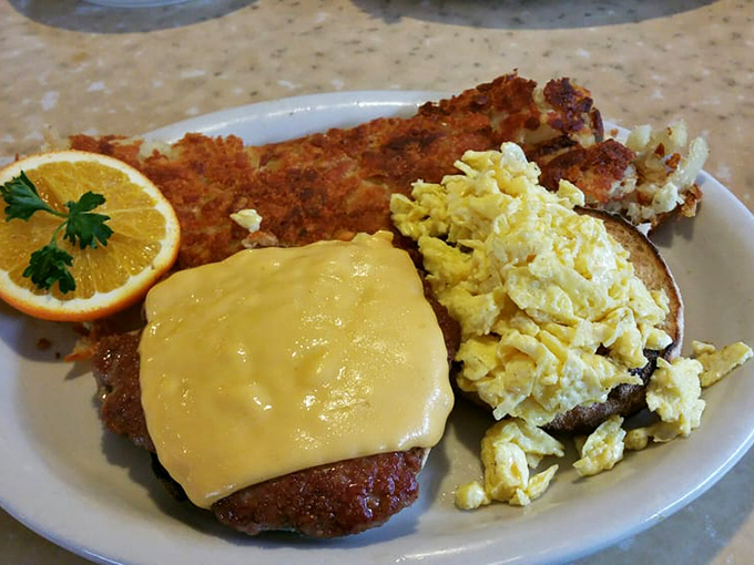 Breakfast perfection on a plate: golden hash browns, eggs that practically glow, and a sausage patty wearing a cheese hat like it's at a Wisconsin game.