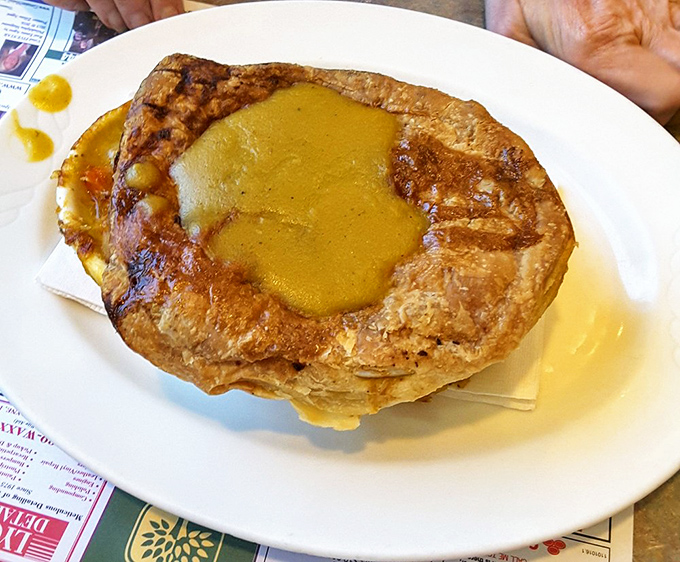 The chicken pot pie arrives like a golden-domed cathedral of comfort, steam escaping with aromas that instantly transport you to grandma's kitchen.