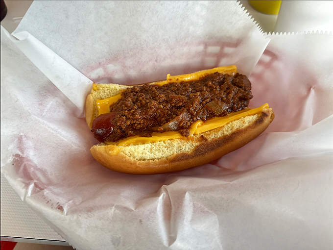 The chili cheese dog arrives like a beautiful mess, demanding both your full attention and a stack of napkins the height of a small novel.
