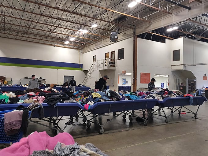 Clothing archipelagos spread across the warehouse floor, where patient shoppers wade through fabrics like textile archaeologists on a mission.