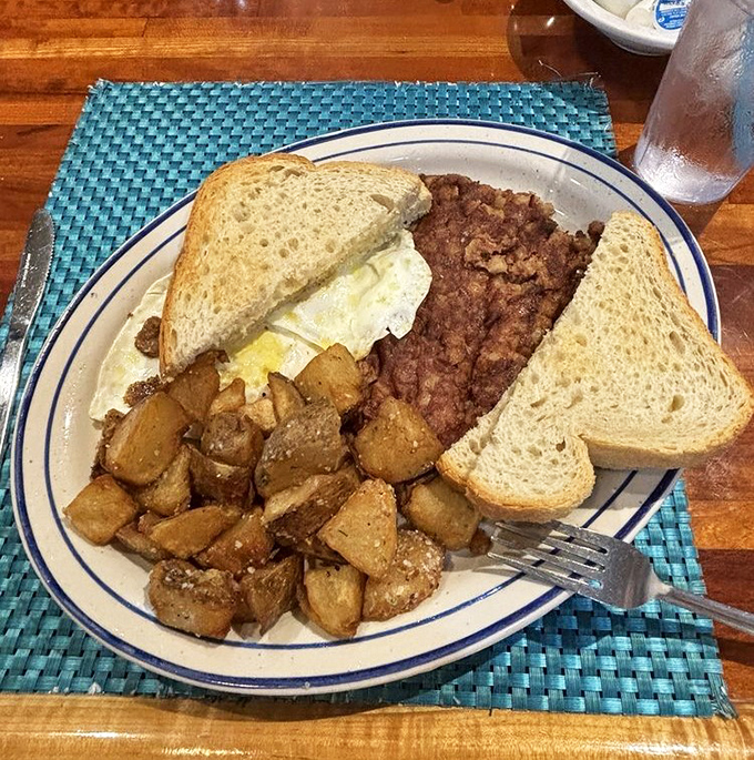 Breakfast of champions: perfectly seasoned potatoes, hearty corned beef, and eggs that would make a rooster proud. Simple perfection on a blue-rimmed plate.