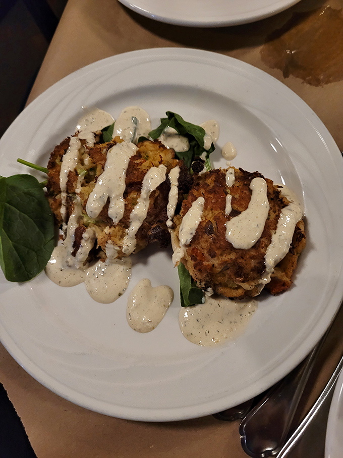 Two perfectly seared crab cakes with just enough sauce to complement, not drown, the sweet crab meat within.