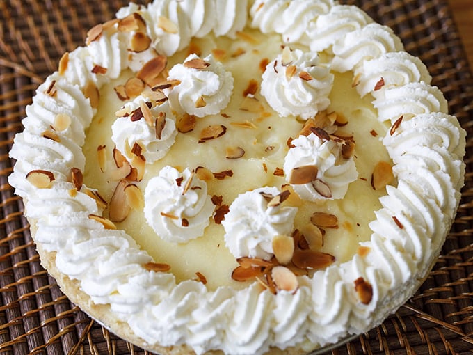 The coconut cream pie wears its toasted almond confetti like jewelry, daring you to resist its creamy siren call.