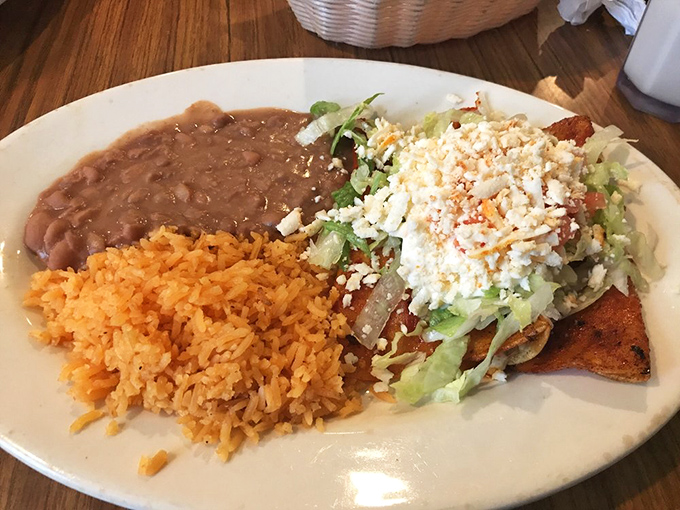 Behold the holy trinity of Mexican comfort: perfectly seasoned rice, beans that weren't rushed, and enchiladas that make fast-food versions weep with inadequacy.
