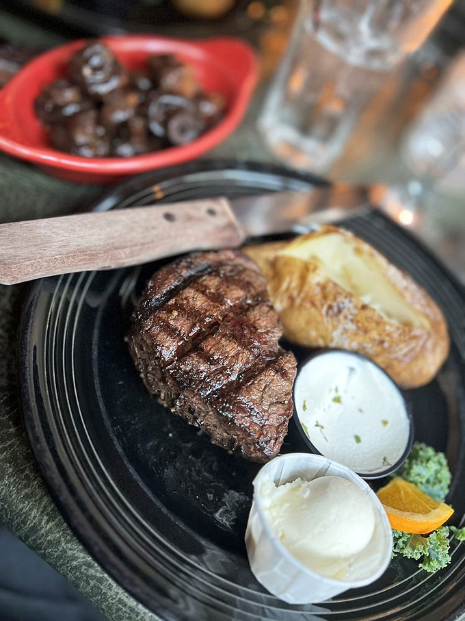 A perfectly grilled filet mignon flanked by a loaded baked potato—proof that sometimes the simplest pleasures are worth driving mountain roads for.