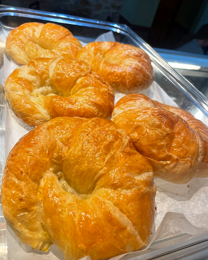 Golden croissants basking in their display case, flaky armor protecting buttery treasures within. Morning has officially arrived.