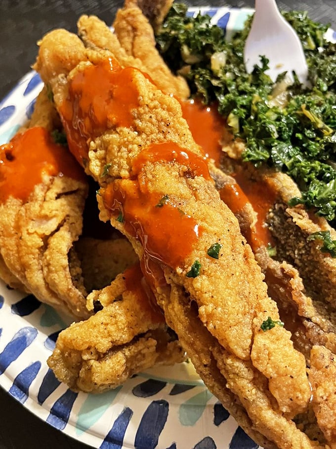 These crispy fish strips drizzled with hot sauce alongside vibrant collard greens prove that seafood and soul food make beautiful music together.