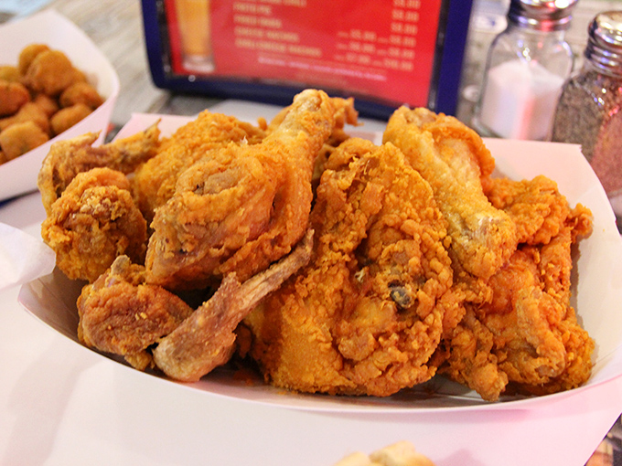 The holy grail of comfort food arrives on paper, not porcelain. Each piece glistening with that perfect crispy coating that audibly shatters with every bite.