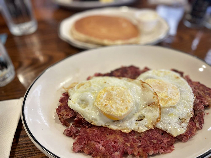 Corned beef hash supporting sunny-side-up eggs like the world's most delicious pedestal. This is breakfast architecture at its finest.