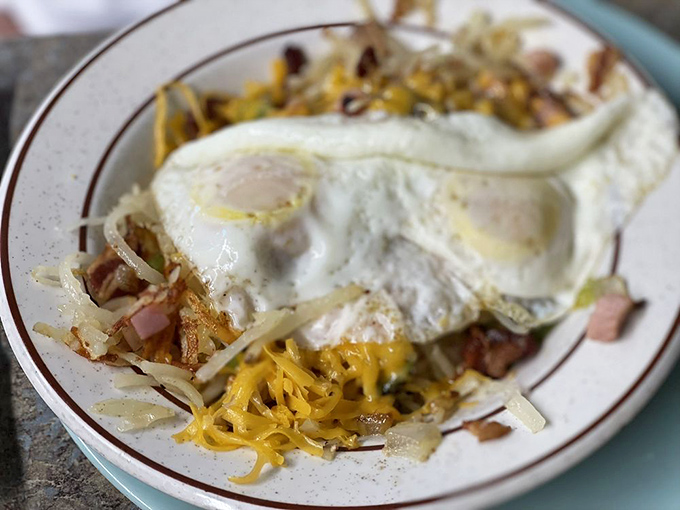 Eggs, perfectly cooked, lounging atop a mountain of hash browns, ham, and cheese—breakfast architecture at its finest.