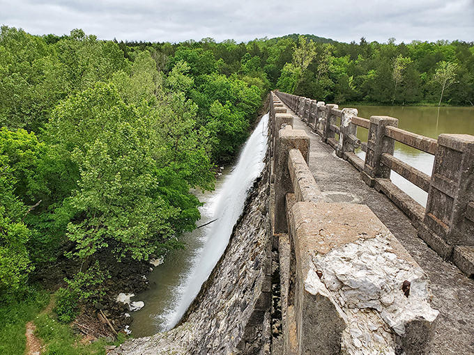 Lake Leatherwood's spillway offers a dramatic contrast: peaceful waters above, rushing cascade below, and everywhere the lush green embrace of the Ozarks.