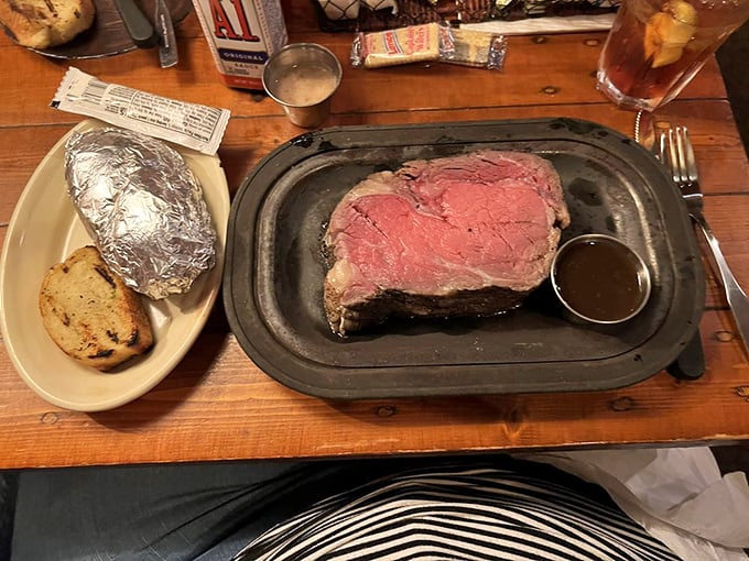 The large cut prime rib arrives with military precision - beautifully medium-rare beef alongside a baked potato standing at attention in its foil jacket.