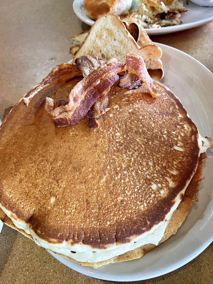 This isn't just a pancake&mdash;it's a golden-brown frisbee of joy with bacon standing at attention, ready to salute your taste buds.