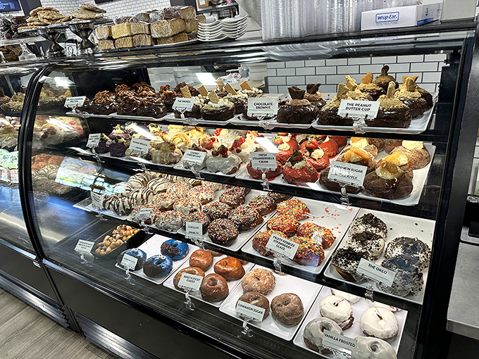 The display case showcases an edible art gallery where the peanut brittle brownie stands proudly alongside strawberry-crowned confections.